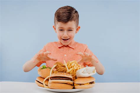 흥분한 어린 소년은 정크 푸드를 본다 파란색 배경에 격리됩니다 스튜디오 테이블에서 고기에 대한 스톡 사진 및 기타 이미지 고기 배경 주제 백인종 Istock