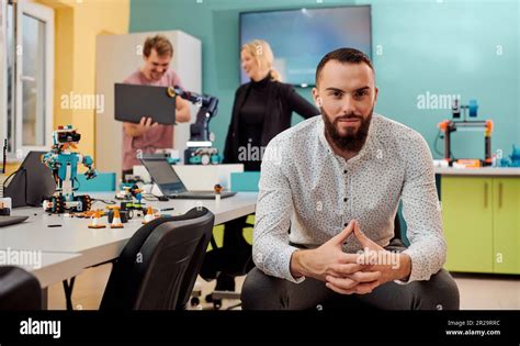 A Man Sitting In A Robotics Laboratory While His Colleagues In The Background Test New Cutting