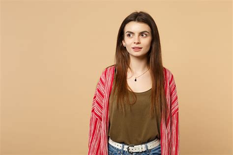 캐주얼에 서 서 예쁜 웃는 젊은 여자의 초상화는 스튜디오에서 파스텔 베이 지 벽 배경에 고립 된 옆에 보고 사람들은 진심으로 감정 라이프 스타일 개념입니다 복사 공간을 모의