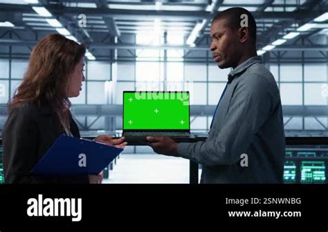 Technicians In Data Center Using Green Screen Mockup Laptop To Develop Disaster Recovery Plans