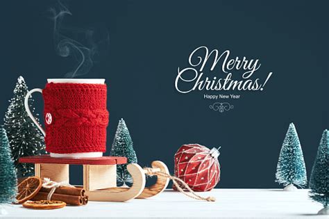 메리 크리스마스 비문 크리스마스 카드입니다 장난감 나무 빨간 그릇 계 피 스틱 및 슬라이스 어두운 배경에 산타 클로스 썰매에 빨간 니트 옷에 뜨거운 코코아와 화이트 컵