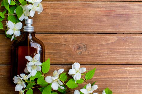 향수 에센셜 오일 어두운 유리 항아리 천연 화장품 천연 향수 꽃 배경 플랫 레이 향기로운 물이 있는 병 나무 배경에 건강한 천연 화장품의 개념 꽃 나무에 대한 스톡 사진 및