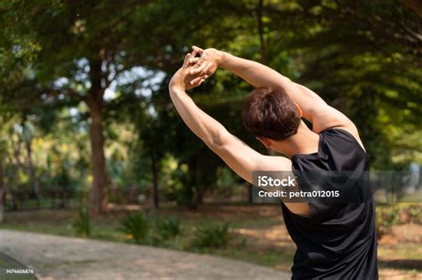 여름날 도시 공원에서 조깅을 한 후 손과 팔을 뻗는 스포티한 잘생긴 남자 젊은 남자는 건강하고 활동적인 라이프스타일을 위해 자연 속에서 야외에서 주말 운동을 하며 좋은