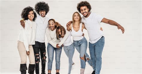 흰색 스튜디오 배경 위에 함께 웃고 포즈를 취하고 흰색 셔츠와 청바지를 입고 카메라를 바라보는 다민족 그룹의 사진 밀레니얼 세대의 우정 라이프스타일 개념 사진