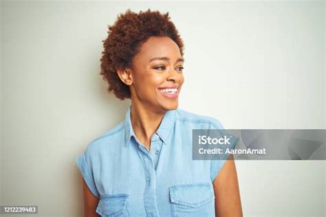 고립된 배경 위에 아프리카 머리를 가진 젊은 아름다운 아프리카 계 미국인 여성은 얼굴에 미소와 함께 옆으로 멀리 찾고 자연스러운 표정 자신감 있게 웃고 있습니다 미소에 대한