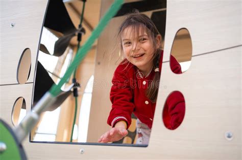 A Cheerful Girl Plays Peek A Boo Through Wooden Play Equipment Capturing A Moment Of Joy Stock