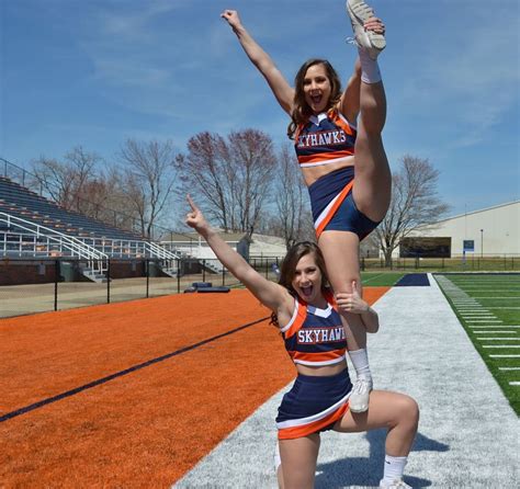 Two Cheerleaders Are Doing Tricks On The Field