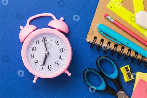Будильник и школьные принадлежности на синем фоне вид сверху Концепция на тему подготовки к