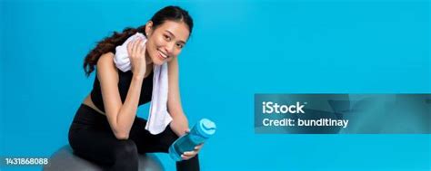 아시아의 아름다운 행복한 여자는 물병을 들고 파란색 배경에 고립 된 운동 후 핏 볼에 앉아 있습니다 슬림하고 건강한 소녀 운동의 개념 체육관에 대한 스톡 사진 및 기타