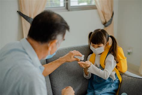 아시아 할아버지는 학교에 가기 전에 손녀 손에 항균 손 소독제를 분출하고 어린 소녀는 코로나바이러스와 독감 발병 시 얼굴 마스크를 착용합니다 2명에 대한 스톡 사진 및 기타