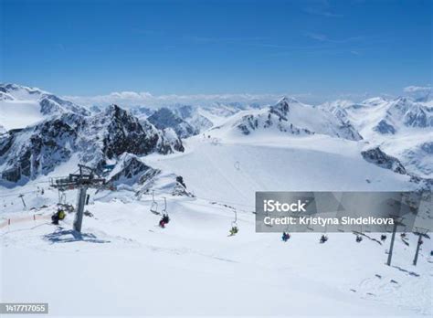 봄철 화창한 날에 Stubai Gletscher 스키 리조트의 의자 리프트에서 눈이 덮인 산 경사면과 피스테와 스키어가있는 겨울 풍경의 와일드 스피츠 꼭대기에서 경치를 감상