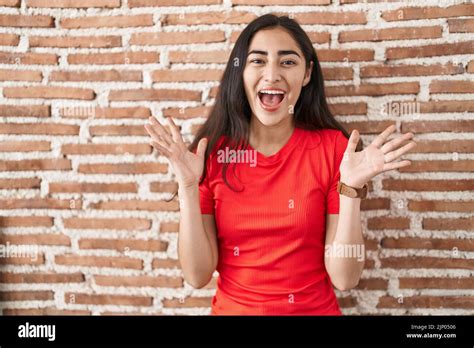 Young Teenager Girl Standing Over Bricks Wall Celebrating Crazy And