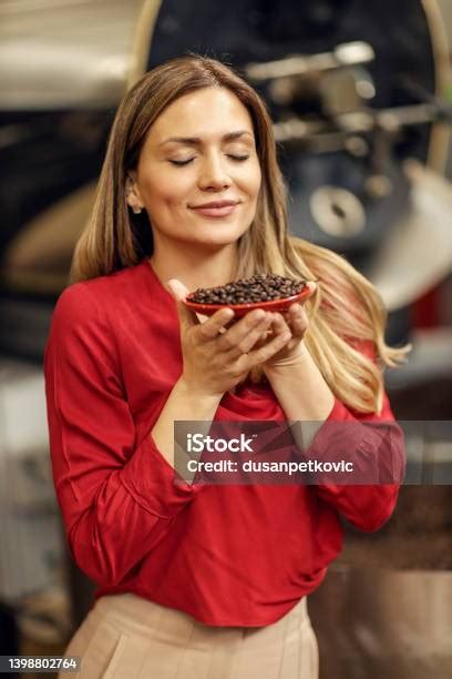 Seorang Wanita Mencium Aroma Biji Kopi Panggang Sambil Berdiri Di Pabrik Kopi Foto Stok Unduh