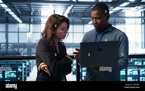 Developers In Data Center Workspace Coding On Laptop Analyzing Metrics