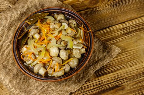 당근 양파 향신료를 곁들인 맛있는 양념 버섯을 세라믹 그릇에 담긴 나무 테이블 위에 올려놓습니다 맨 위 보기 갈색에 대한 스톡