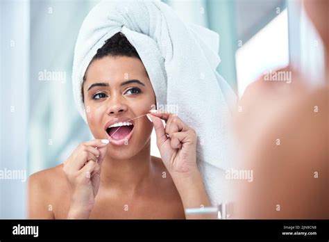 Flossing For Healthier Teeth A Woman Flossing Her Teeth While Wearing
