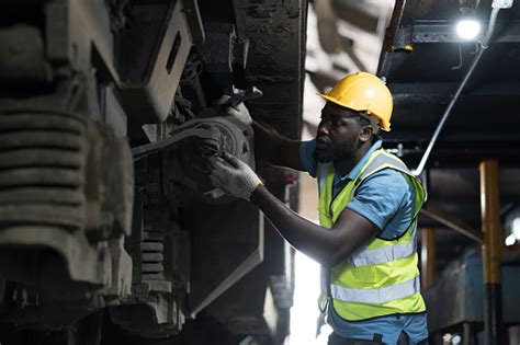 남성 엔지니어 유지 보수 기관차 엔진 기관차 수리 차고에서 안전 유니폼 헬멧 및 장갑을 착용 남성 철도 엔지니어는 기차 차고에서 렌치 수리 기차 바퀴를 사용합니다 25 29