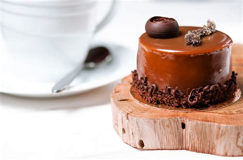 화이트 테이블에 흰색 컵 옆에 있는 나무 스탠드에 초콜릿 조각이 있는 맛 있는 초콜릿 케이크가 놓여 있습니다 그릇에 대한 스톡 사진 및 기타 이미지 Istock