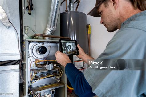 젊은 남성 재산 검사관은 주거용 주택 차고 내부의 용광로 온수 히터와 에어컨 장치를 촬영합니다 전기로에 대한 스톡 사진 및 기타