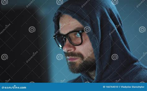 Male Hacker In The Hood And Glasses Working On A Computer In A Dark