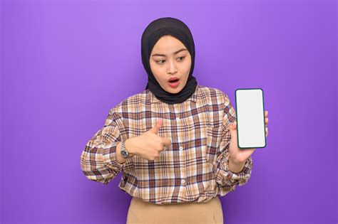격자 무늬 셔츠를 입은 젊은 아시아 여성이 빈 화면 휴대 전화를 보여주고 보라색 배경에 고립 된 엄지 손가락을 몸짓으로 보여줍니다 20 24세에 대한 스톡 사진 및 기타