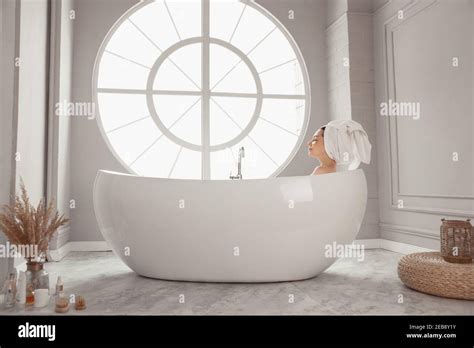Young Woman Relaxing Lying In Bathtube In Luxury Bathroom With Round