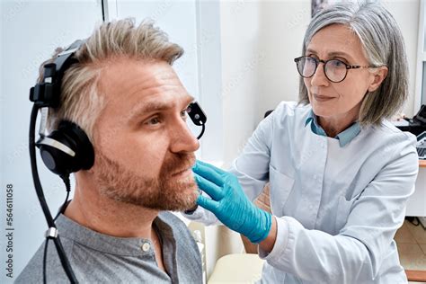 Mature Man Receives Tympanometry With Audiologist Using Tympanometer At Audiology Clinic