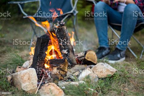 아름 다운 커플 앉아 캠프 파이어 주위에 캠핑 텐트와 배경에 남자 막대기로 화재 제스처 건강한 생활방식에 대한 스톡 사진 및 기타 이미지 Istock