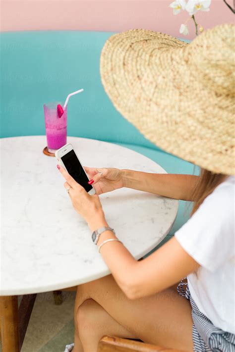 Anonymous Girl In Straw Hat Relaxing In Cafe And Using Mobile By Stocksy Contributor Nikita