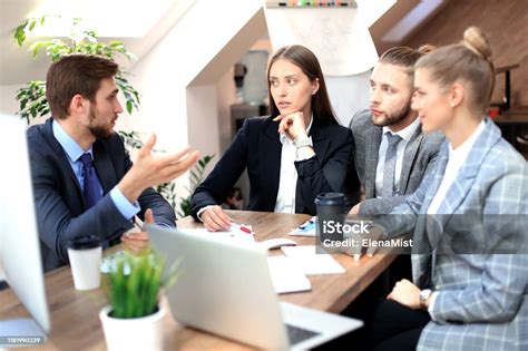 동료들과 함께 사무실 책상에 앉아있는 동안 의사 소통 일하는 젊은 비즈니스 사람들의 그룹 경영자에 대한 스톡 사진 및 기타 이미지 Istock