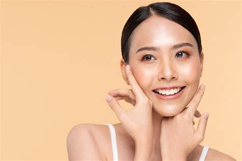 아름다운 아시아 젊은 여자 감동 부드러운 뺨 미소 와 깨끗 한 신선한 피부 행복과 쾌활 한 감정 베이지 배경에 고립 된 뷰티 화장품 및 얼굴 치료 개념 20 24세에 대한