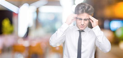 젊은 사업가 머리에 손을 가진 고립 된 배경 위에 안경을 쓰고 있기 때문에 머리가 아파 서 스트레스를 받았습니다 고통 편두통 걱정하는에 대한 스톡 사진 및 기타 이미지