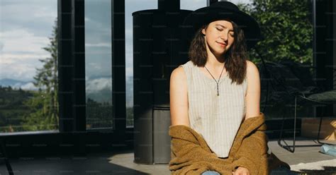 현대적인 객실에서 햇살이 내리쬐는 세련된 젊은 여성 창문과 산 언덕의 배경에 햇빛 아래 바닥에 앉아 있는 세련된 힙스터 여성