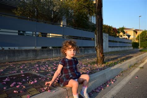 Premium Photo Portrait Of Girl Sitting On Curb In City