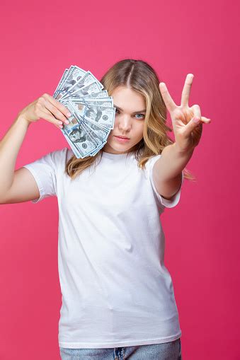 한 우월한 백인 소녀는 산호 배경에 대한 V제스처를 보여주면서 미국 통화 지폐를 잔뜩 포즈를 취합니다 20 24세에 대한 스톡 사진 및 기타 이미지 Istock