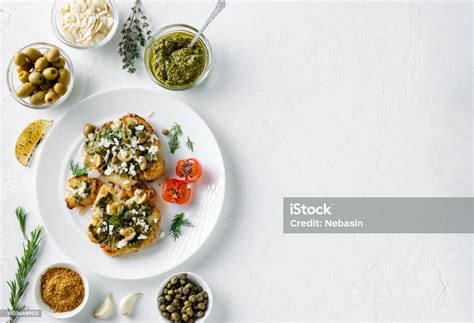 향신료 치미추리 소스 아몬드 플레이크 올리브 튀긴 체리 토마토 케이퍼가 있는 콜리플라워 스테이크를 화이트 플레이트에 얹습니다 채식 음식 흰색 배경입니다 복사 공간을 참조