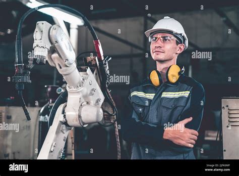 Young Factory Worker Working With Adept Robotic Arm In A Workshop