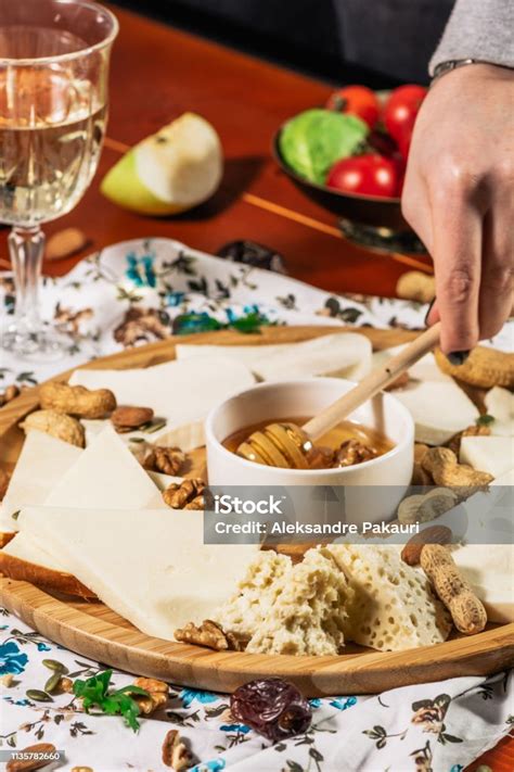 화이트 와인 Guda 치즈 치즈 강판 나무 껍질 하드 치즈 슬라이스 호두 포도 크래커 꿀 술 총 밝은 나무 배경으로 제공 되는 둥근 나무 보드 플레이트에 모듬 치즈 0명에