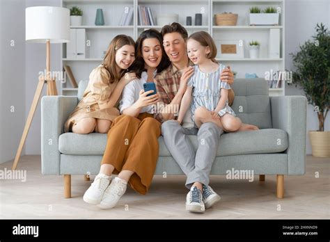 Frohe liebevolle Familie Junge Mutter Vater und Töchter telefonieren