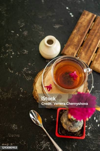 검은 색 배경에 봄 히아신스 꽃이있는 투명한 컵에 차 한 잔 머그잔은 나무 프레임 위에 서 있으며 그 옆에는 금속 숟가락과 흰 꽃병이 있습니다 복사 공간 0명에 대한 스톡