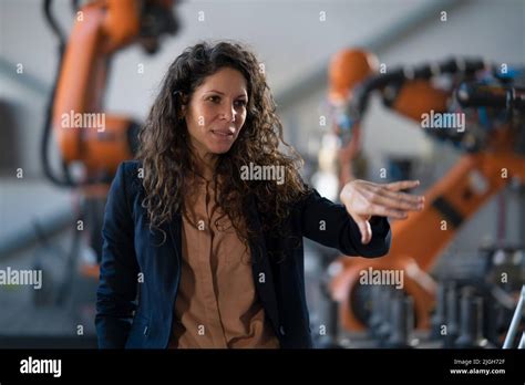 Automation Female Engineer Talking To Somebody About Programming Robotic Arm In Factory Stock