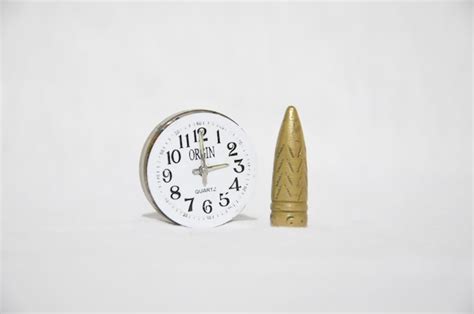 Premium Photo Close Up Of Clock With Bullet On White Background