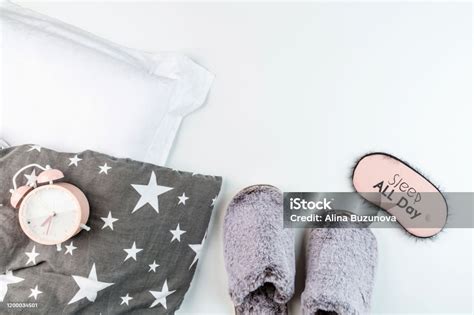 흰색 배경에 고립 된 부드러운 푹신한 슬리퍼 회색 베개 눈가리개 및 분홍색 알람 시계가있는 플랫 레이 상단 보기 오버 헤드 모형 템플릿 휴식 시간 가정 생활에 대한 스톡