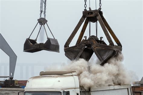 강 항구에서 트럭에 선박에서 시멘트 클링커를 하역 그래플 크레인 먼지가 많은 벌크화물의 바지선 배달 갠트리 크레인 하역 및 하버 야외에서 적재 물류 벽돌에 대한 스톡 사진