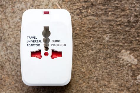 여행에 사용되는 범용 전기 소켓 플러그 어댑터를 닫습니다 전 세계 여러 전기 콘센트에 연결하는 데 사용됩니다 어두운 배경에 격리 된 전기 어댑터 콘센트에 대한 스톡 사진 및