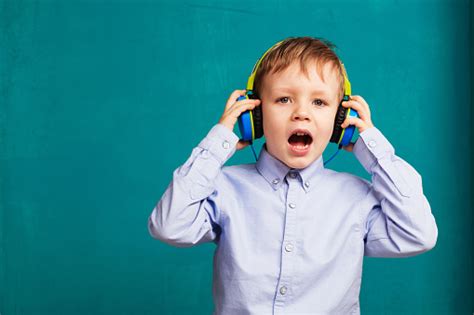 서 고 녹색 파란 벽에 스마트폰 통해 헤드폰에서 음악을 듣고 밝은 헤드폰에 잘생긴 작은 세련 된 소년 귀여운에 대한 스톡 사진