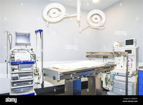 Empty veterinary operating room equipped with surgical lights, monitors, anesthesia machine, and ...