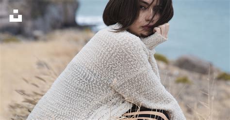 낮 동안 갈색 잔디밭에 앉아 있는 흰색 니트 스웨터를 입은 여자 사진 Unsplash의 무료 의류 이미지