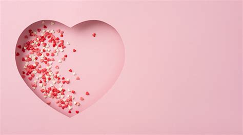 분홍색 배경에 빨간색과 흰색의 작은 사탕이 있는 하트 모양의 컷아웃 디자인입니다 발렌타인 데이 컨셉과 로맨틱한 행사에 적합합니다