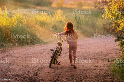 어린 소녀는 일몰에 자연에 시골 도로에 자전거와 함께 간다 두발자전거에 대한 스톡 사진 및 기타 이미지 두발자전거 아이 오븐에 굽기 Istock